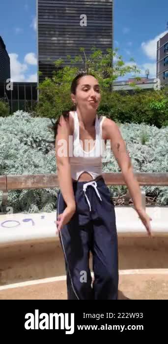 Energetic young woman performing a dynamic dance routine in a city park ...