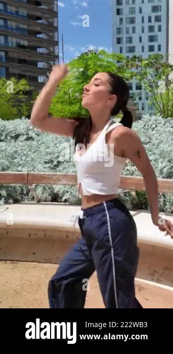 Professional dancer performing dynamic freestyle moves against urban park backdrop, expressing ...