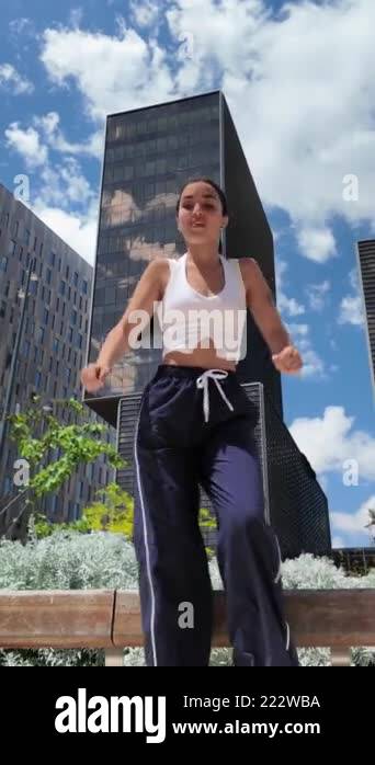 Energetic young woman performs a dynamic dance routine against a ...