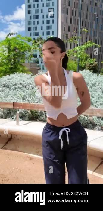 Young dancer performing dynamic dance moves in sunlit urban park ...