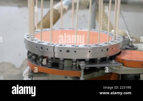 A machine processes wooden dowels, arranging them vertically in a ...