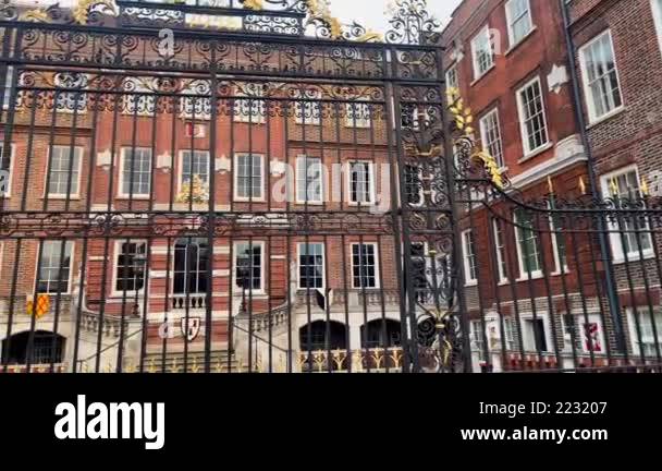 Ornate wrought iron gates with golden details frame a historic red ...