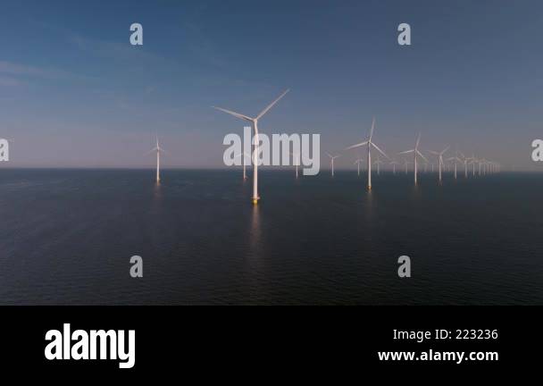 Giant windmill turbines stand tall in the calm waters of the ...