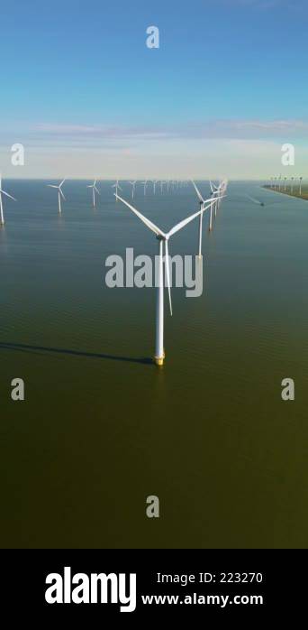 Giant wind turbines spin gracefully above the calm waters, capturing ...