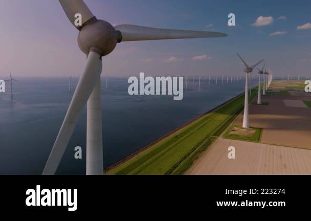 Towering wind turbines along the water in the Netherlands. Windmill ...