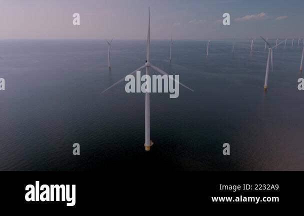 Giant wind turbines spin gracefully over the tranquil waters of the ...