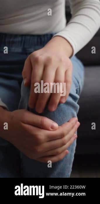 Vertical video of young caucasian female touching her leg feeling pain ...