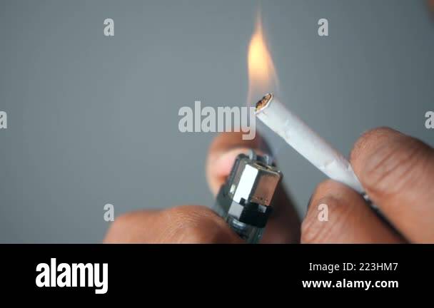 A detailed closeup of a hand carefully lighting a cigarette using a ...