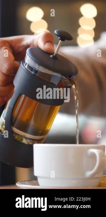 Gently pouring the freshly brewed and aromatic tea from a French press ...