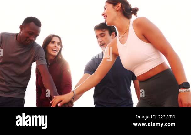 Low-angle shot of a diverse group of friends cheerfully joining their hands together ...