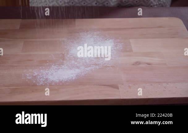 Food preparation. Close-up of a wooden kitchen board on which flour is ...
