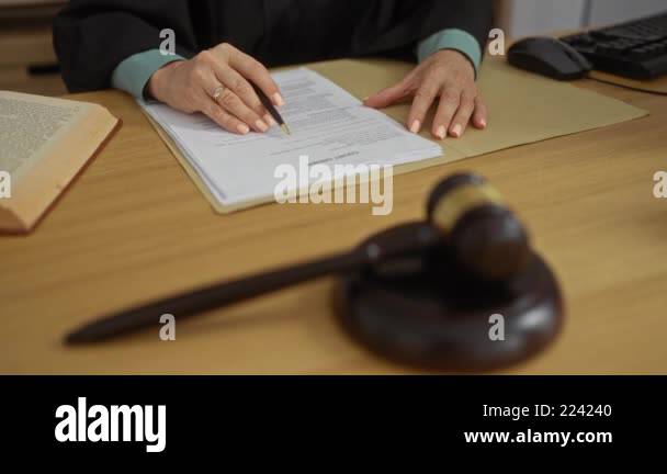 Female judge reviewing documents in a courtroom with a gavel on the ...
