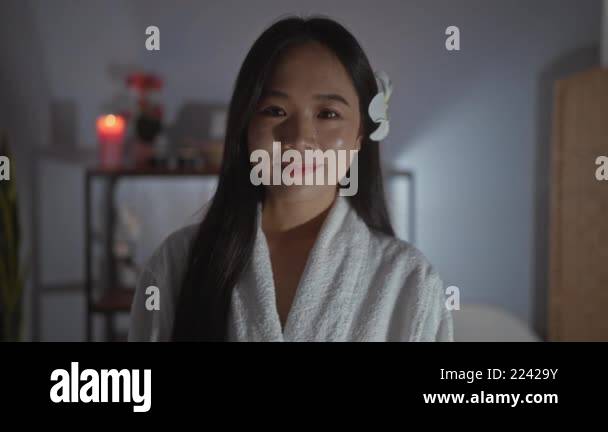 Beautiful woman in a spa wearing a white robe with a flower in her hair ...