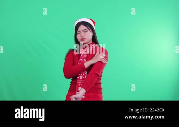 Girl wearing Christmas sweater, Santa hat and scarf, showing pain ...