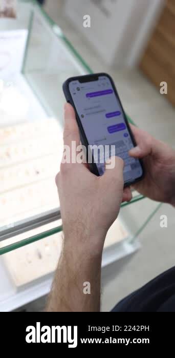 Close-up of hands texting on a smartphone in a jewelry store, browsing ...