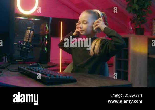Teenager little girl gamer streamer put on headphones looking at camera ...