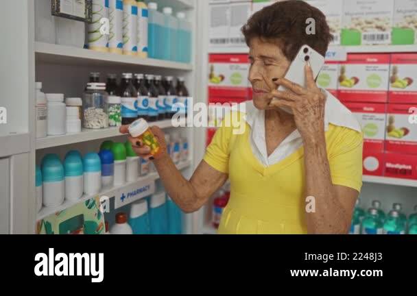 A mature woman in a yellow dress is using her phone while examining a ...