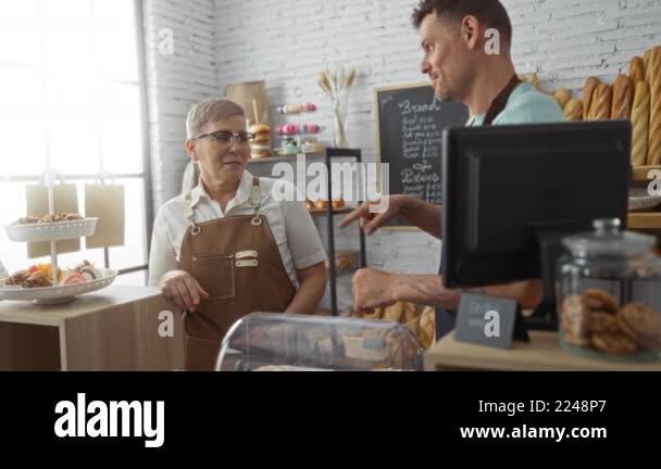 Woman and man working as bakers in a cozy indoor bakery shop filled ...