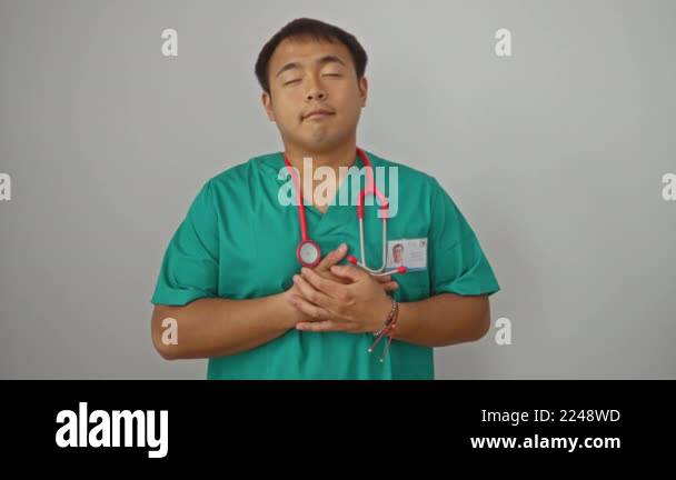 Doctor, young chinese man in medical uniform gratefully holding chest ...