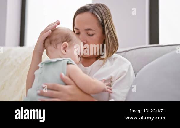 Relaxed mother and daughter sharing a lovely kiss, sitting together on ...