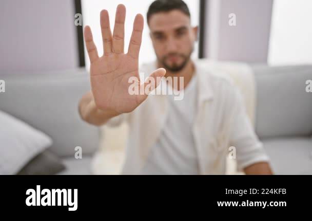 Cheerful young arab man sitting on sofa at home, ecstatically counting ...
