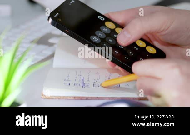 hand holding calculator checking off tasks office table notebook pen ...