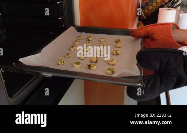 Hands wearing oven mitts pick up the baking tray sheet with warmed ...