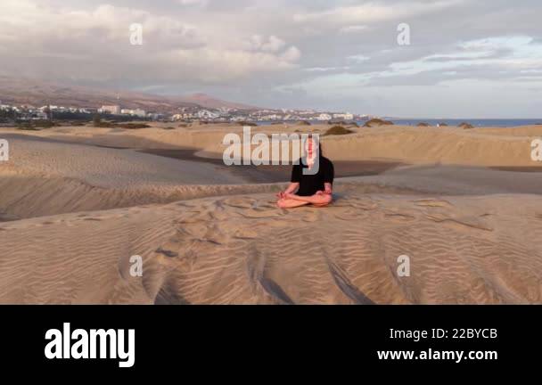 A girl engages in meditation on the soft sands of Gran Canarias dunes ...