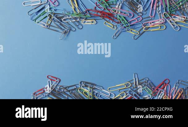 Colorful paper clips are scattered across a blue background, with copy ...