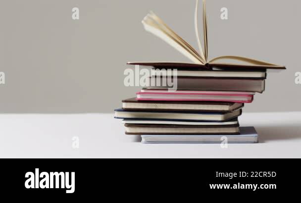A stack of various books sits against a plain background, with copy ...
