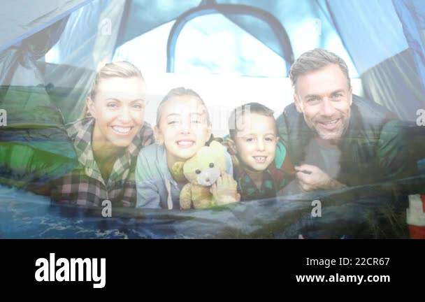 Family camping in tent, smiling children holding teddy bear over ...