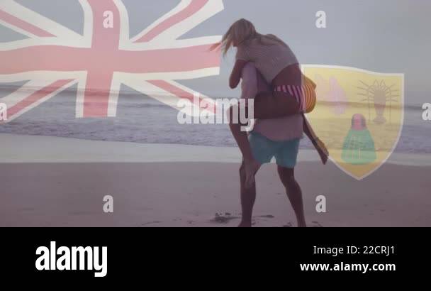 Walking on beach, couple holding British flag and Turks and Caicos coat ...