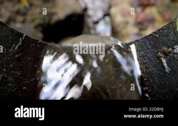 Closeup of water flowing through drainage pipe channel in serene ...