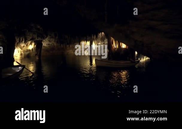 Boatman rowing a boat filled with tourists through the enchanting caves ...