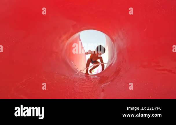 Young boy sliding down a vibrant red water slide, laughing joyfully ...