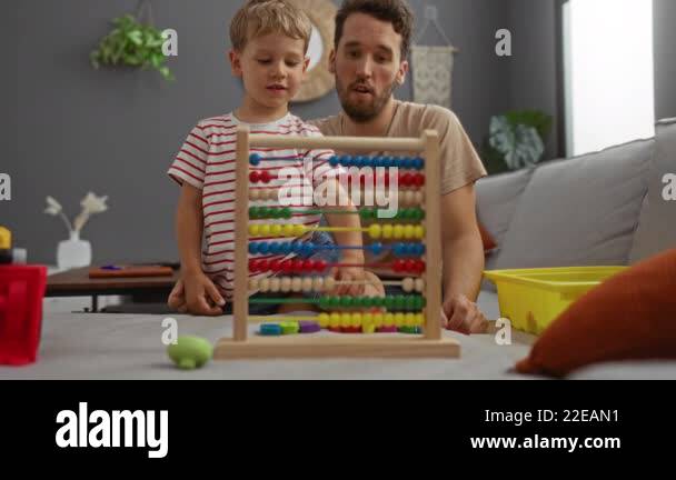 Father teaching son with colorful abacus in cozy living room ...