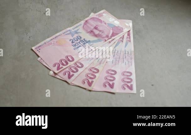 Turkish banknotes of 200 lira are spread out on a concrete surface ...