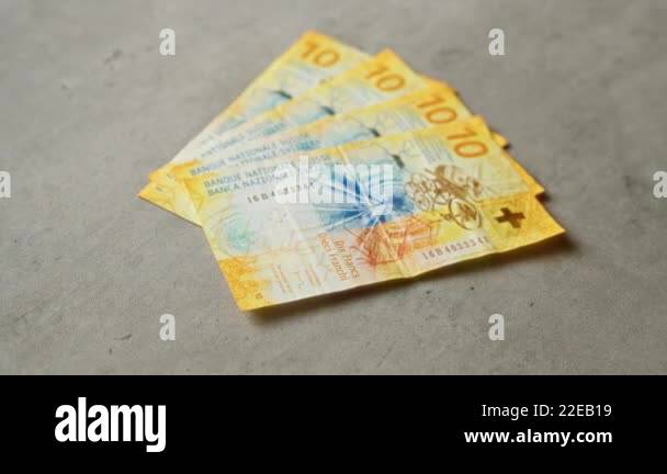 Swiss 10 franc banknotes fanned out on a rough concrete surface ...