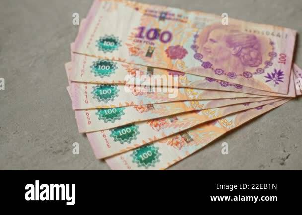 Argentinian pesos banknotes fanned out on a concrete surface ...