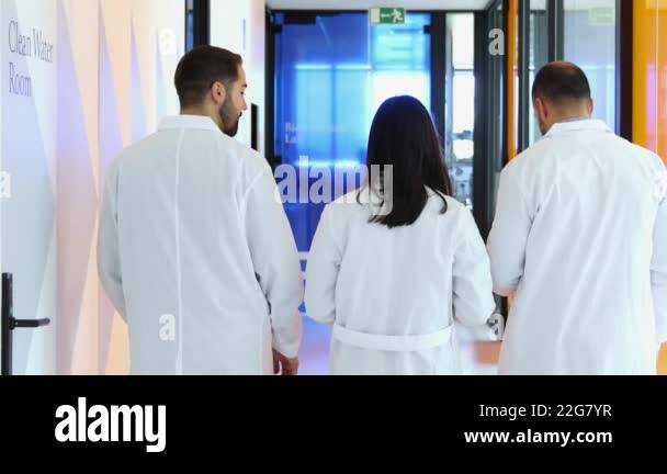 Research team members in white coats walk down corridor of modern ...