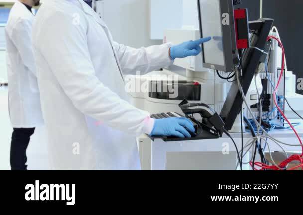 Laboratory technician in a white lab coat operates sophisticated ...