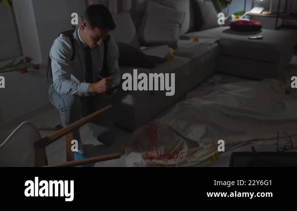 Hispanic man investigating a crime scene indoors, with evidence markers ...