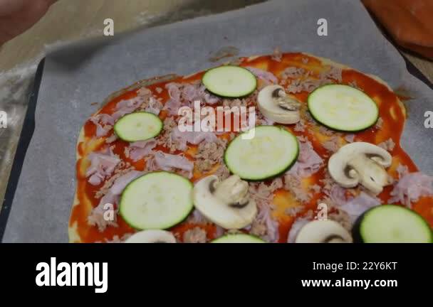 Young family members collaborating while spreading tomato sauce, adding ...