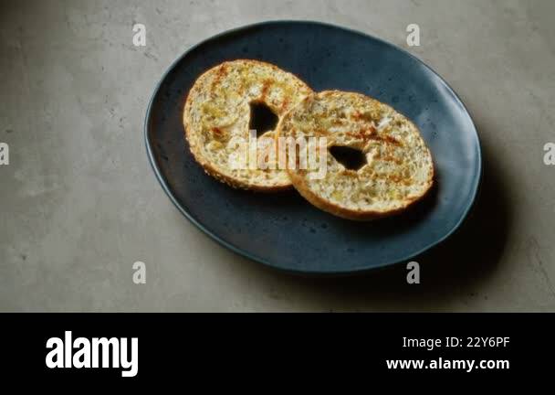 Toasted bagels on a dark plate placed on a light concrete surface ...