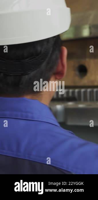 An industrial worker is attentively observing the operation of heavy ...