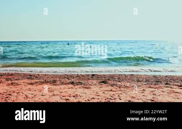 Waves gently rolling onto pebbly shore under clear sky at Aegean Sea ...