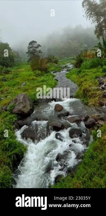 Panorama of the river upstream with rocks and surrounded by green grass ...