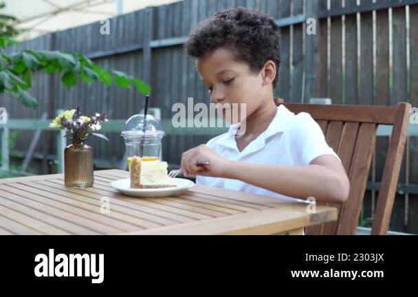 hungry african american teenager eating cheesecake with fork in park ...