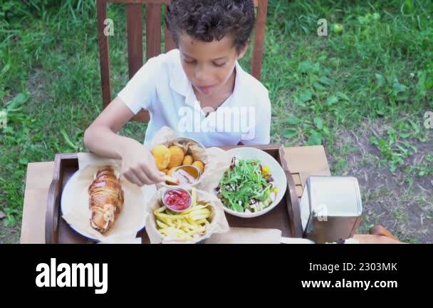 hungry african american teenager eats french fries with ketchup in park ...