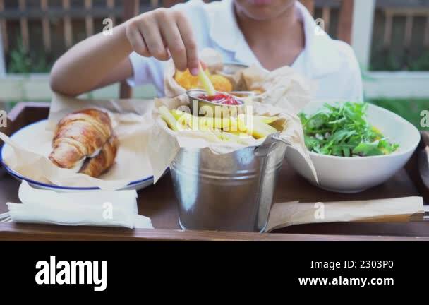 hungry african american teenager eats french fries with ketchup in park ...
